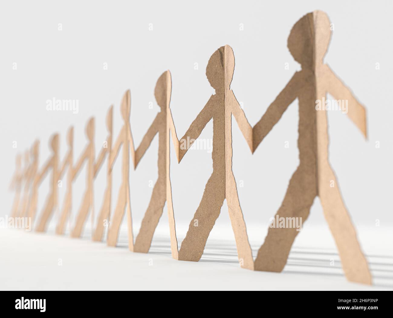 A row of brown cardboard cutout men on an isolated white studio ...