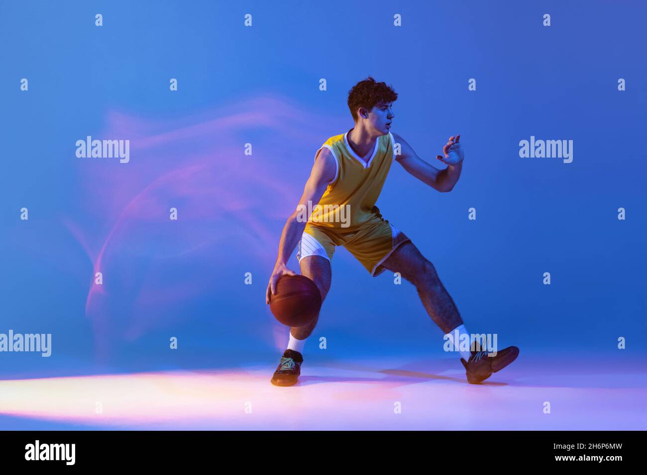 Dynamic portrait of professional basketball player training with ball ...