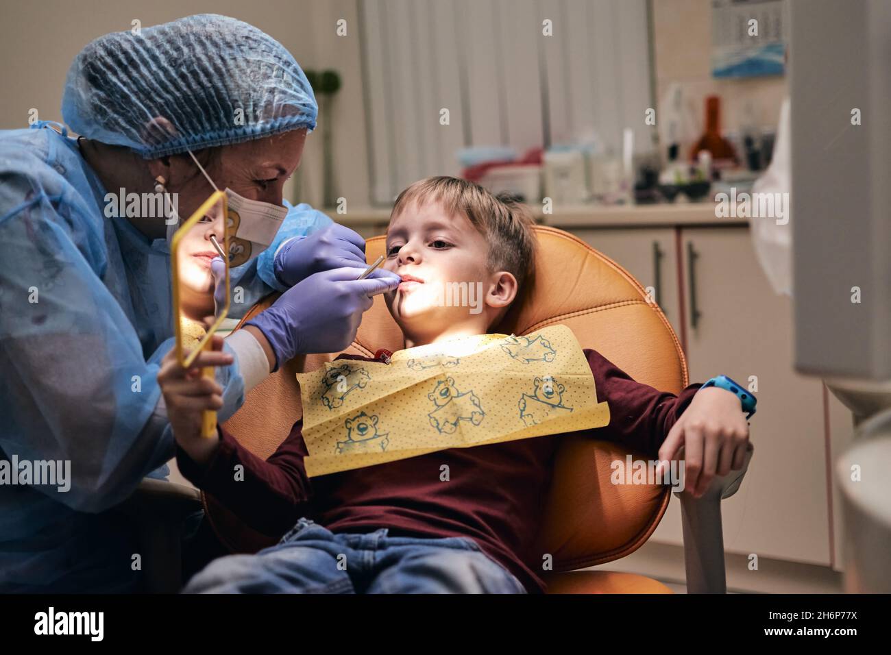 Boy sitting on dental chair with open mouth during oral checking up ...
