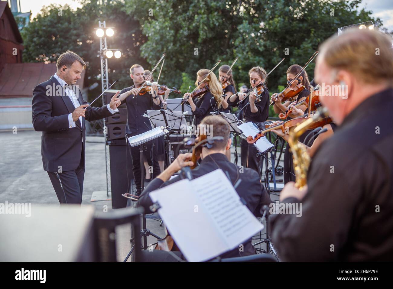 Conductor directing orchestra performance on outdoor stage Stock Photo ...