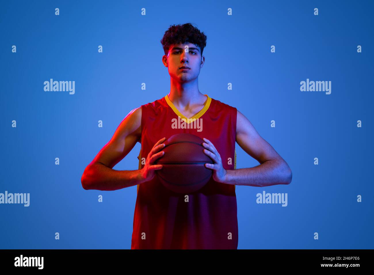 Close-up portrait of young man, basketball player holding ball and ...