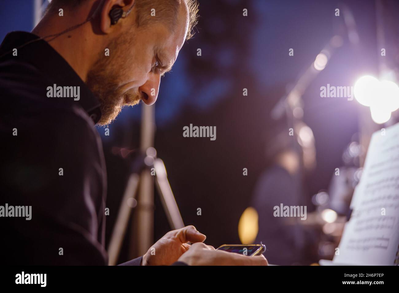 Male musician using cellphone during concert rehearsal at night Stock ...