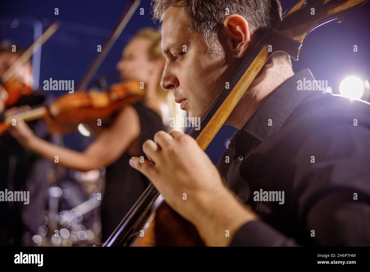 Male musician playing cello at night outdoor concert Stock Photo - Alamy