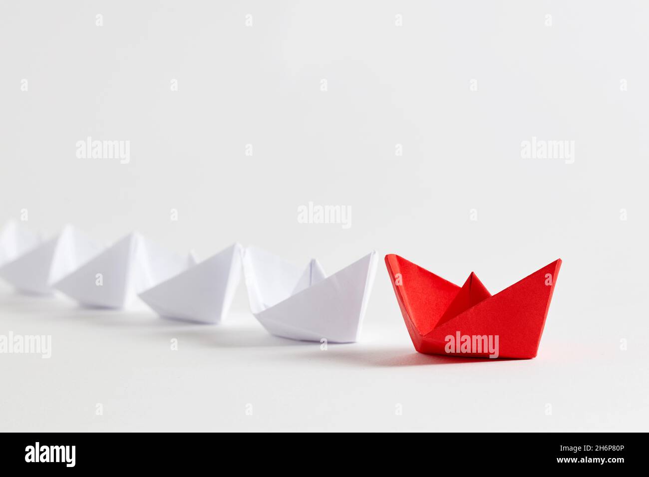 Red paper boat leads white paper ships. Teamwork, collaboration ...