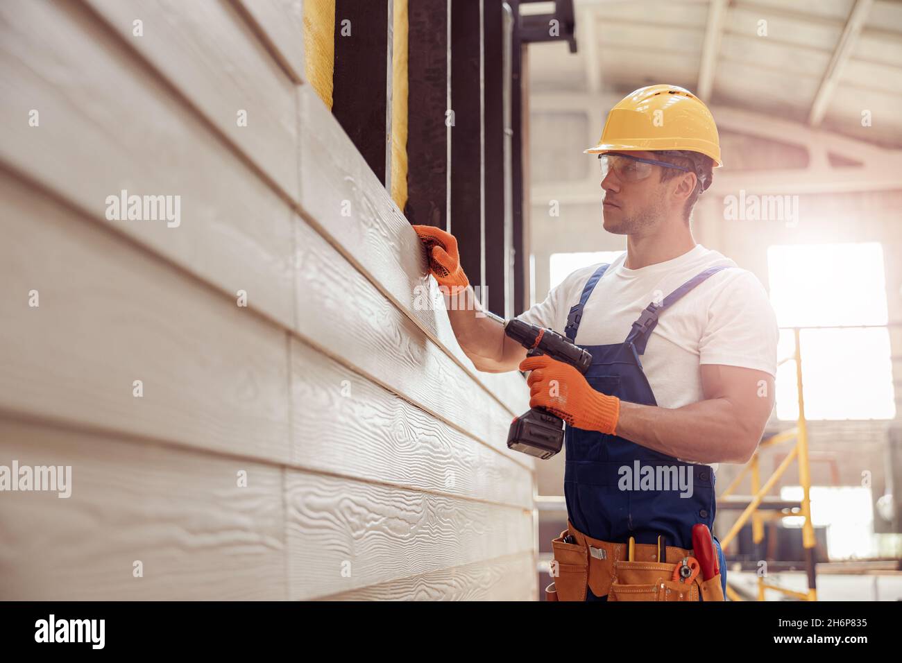 Handsome young man builder installing exterior wood siding Stock Photo ...
