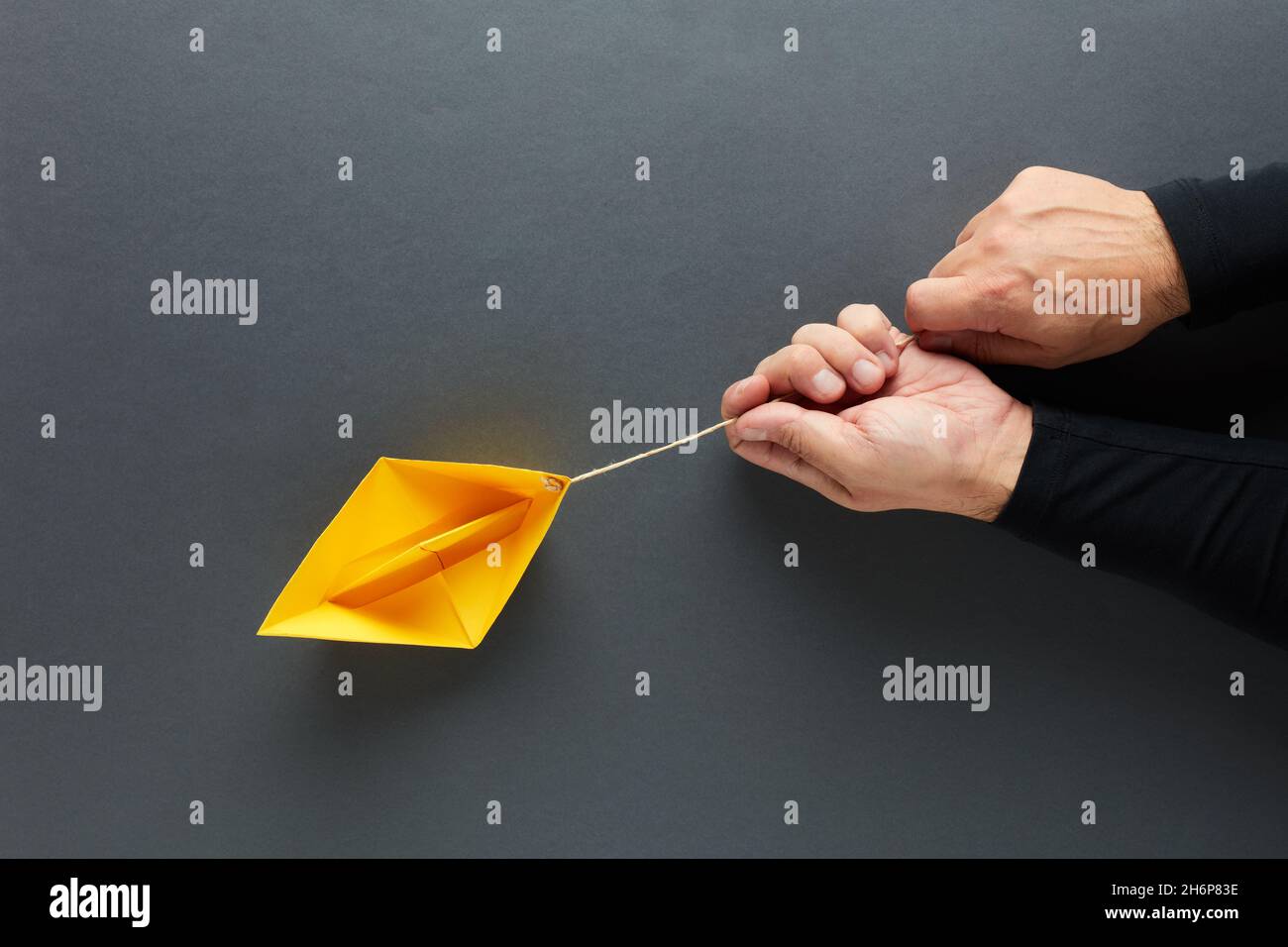 Male hands pull a paper boat with rope. Assistance, support, guidance ...
