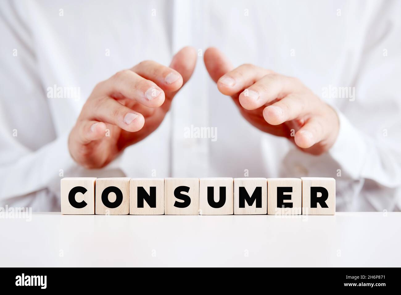 Businessperson hands covering the word consumer written on wooden cubes ...