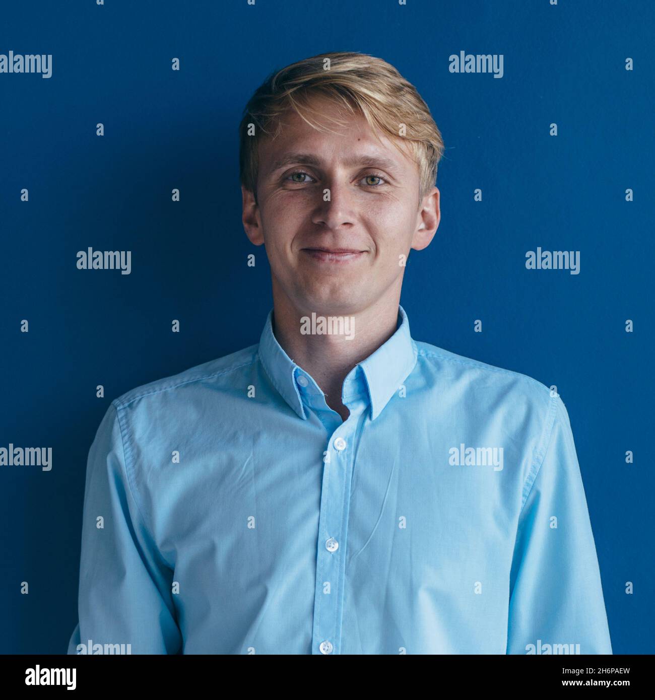 Portrait of a young man standing against blue background Stock Photo ...