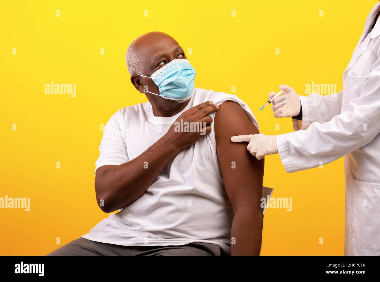 Doctor making vaccine shot against coronavirus to elderly black male ...