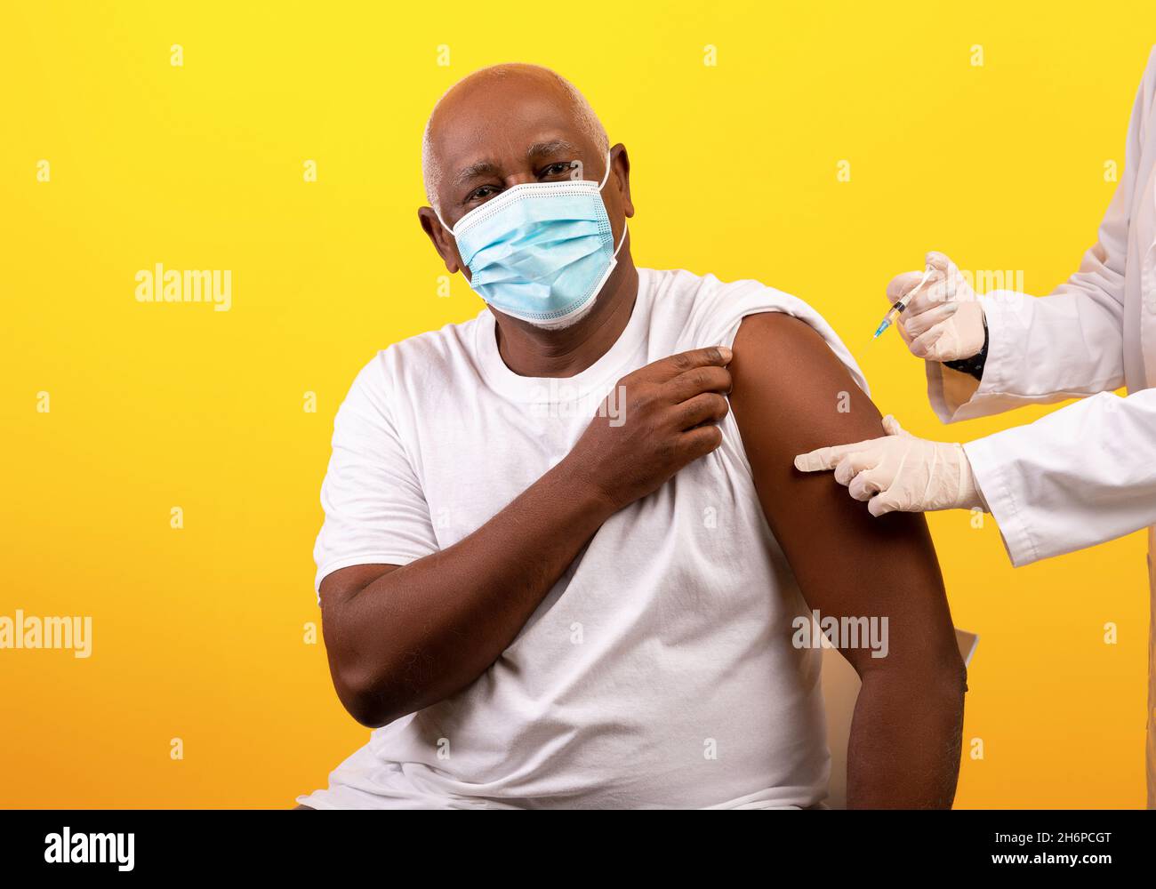Doctor giving coronavirus vaccine shot to senior African American male ...