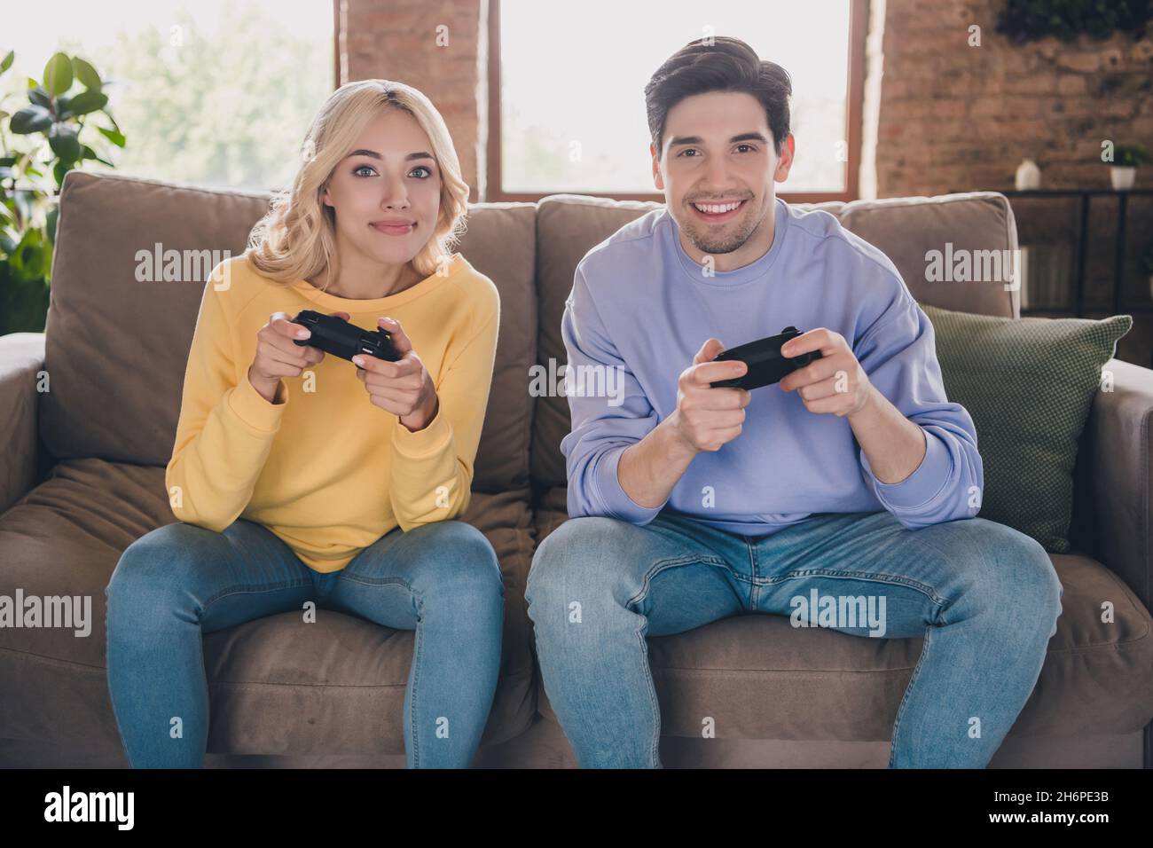 Photo of young couple girlfriend boyfriend play game joystick sit sofa ...
