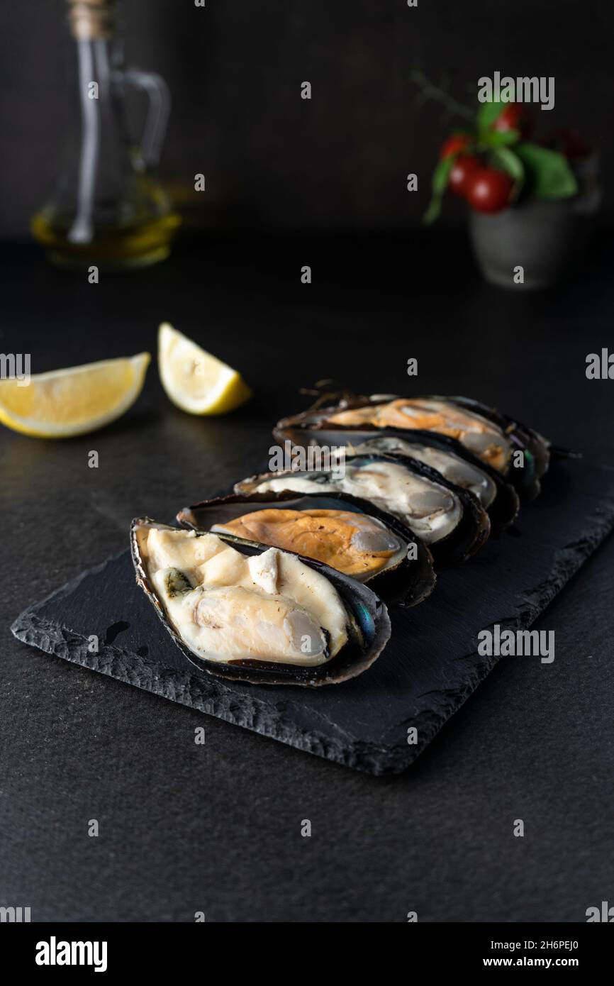 mussels freshly frozen on a plate with ice, on a dark background ...