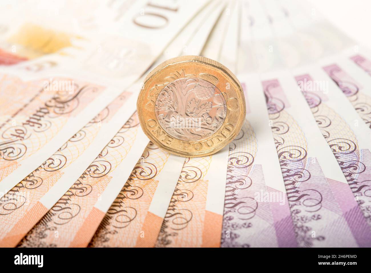 Money: One and two pound coins sat on ten and twenty pound notes. £1 £ ...