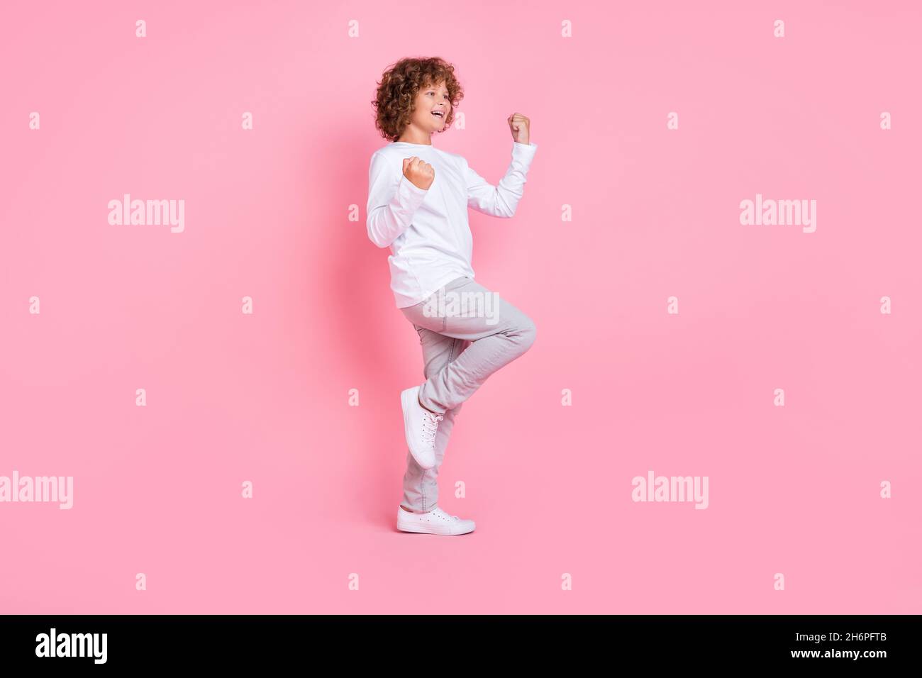 Full size photo of cheerful happy little child raise hands winner look ...