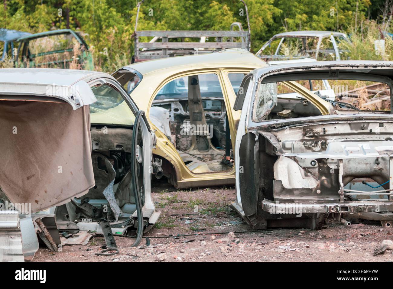 Metal rusty different cars body parts abandoned in greenery. Car dump ...