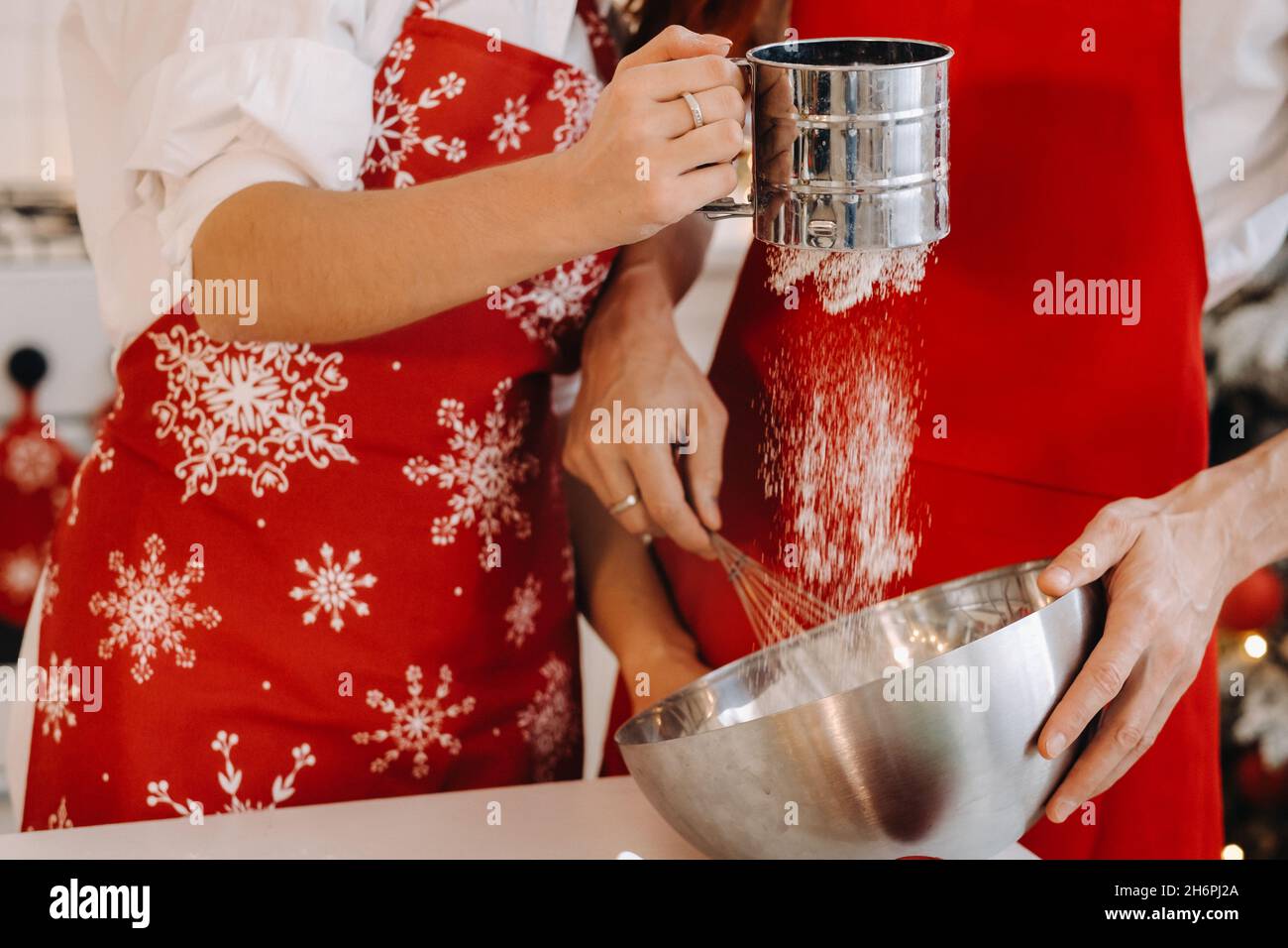Close-up of hands pouring flour into a container for stirring dough ...