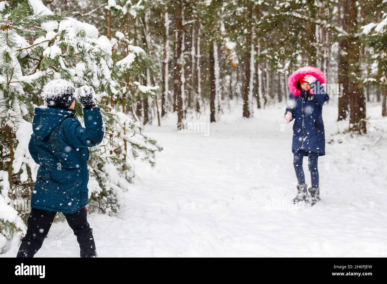 The boy swinging a snowball with a girl. Funny children in Winter Park ...