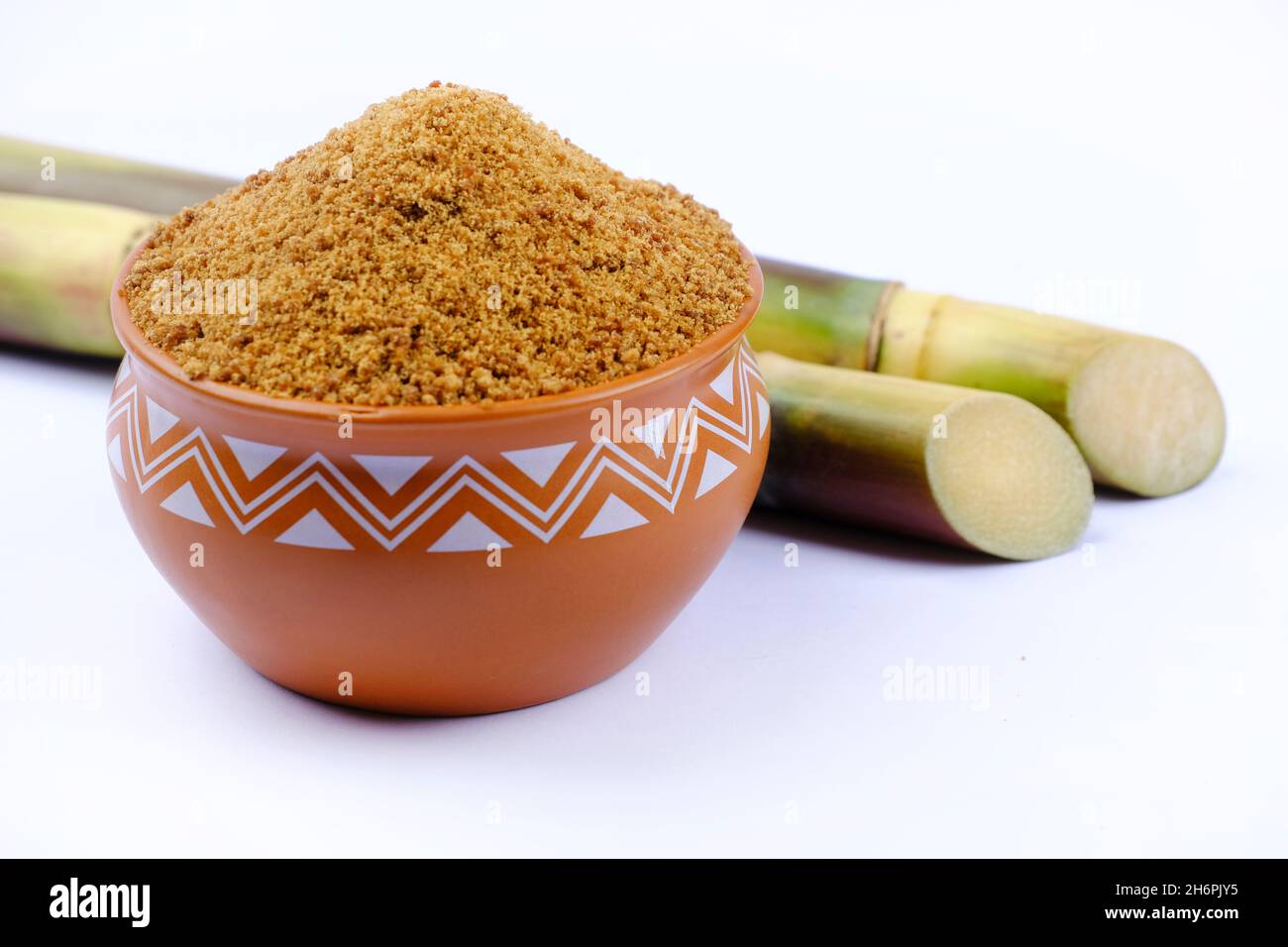 Jaggery powder and sugarcane isolated on white background. Jaggery is ...