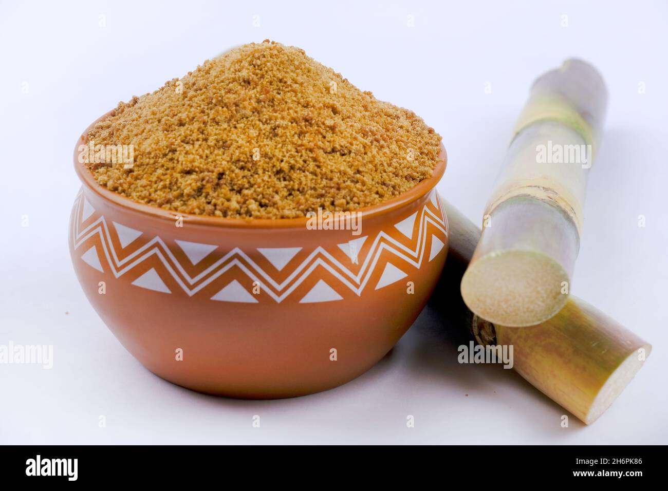 Jaggery powder and sugarcane isolated on white background. Jaggery is ...