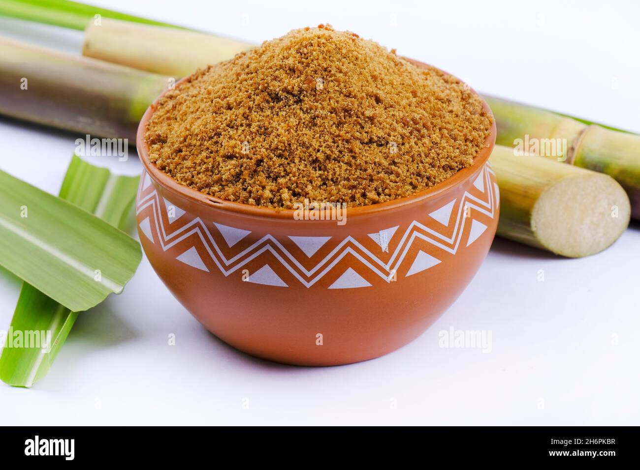 Jaggery powder and sugarcane isolated on white background. Jaggery is ...