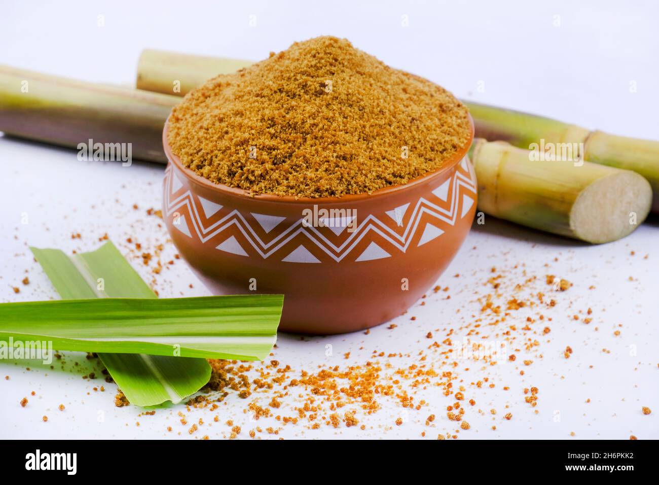 Jaggery powder and sugarcane isolated on white background. Jaggery is ...