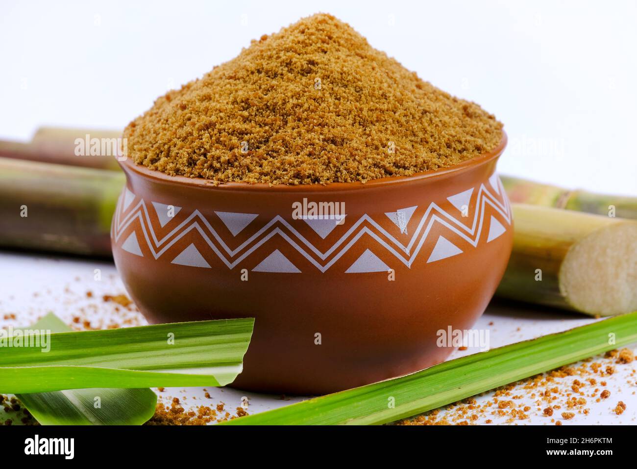 Jaggery powder and sugarcane isolated on white background. Jaggery is ...