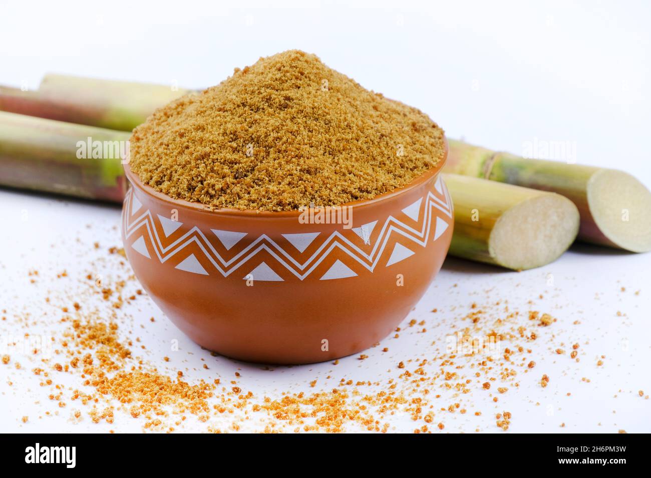 Jaggery powder and sugarcane isolated on white background. Jaggery is ...