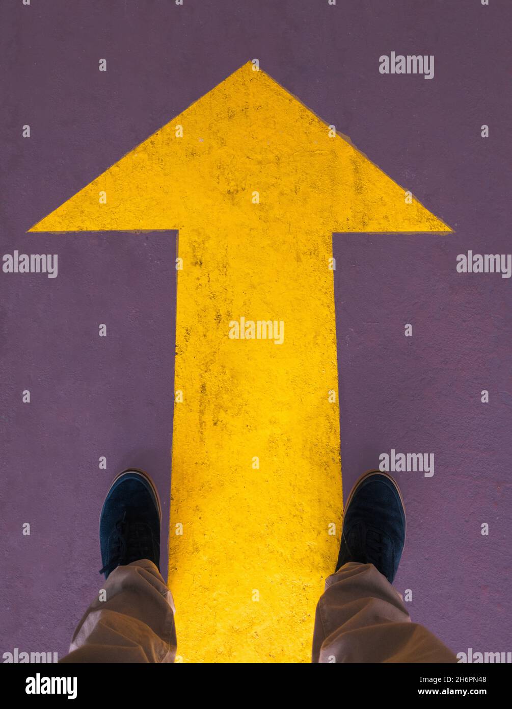 Human standing on a yellow arrow sign Stock Photo - Alamy