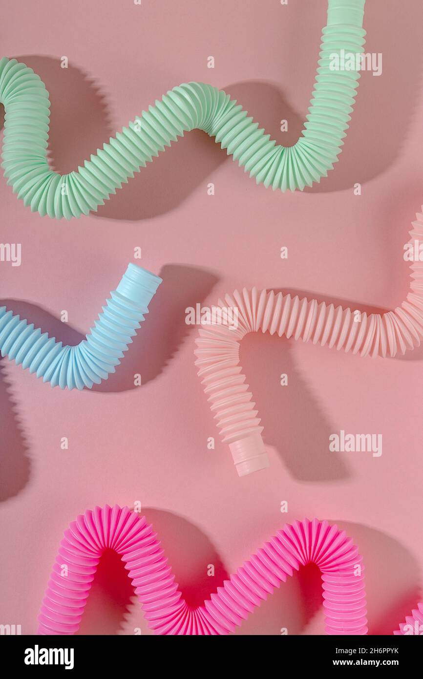 Curved pink blue mint antistress pop tube toy with shadow on pink ...