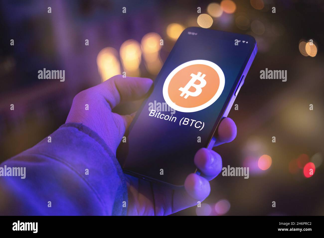 Bitcoin BTC cryptocurrency symbol, logo. Business and financial concept. Hand with smartphone ...