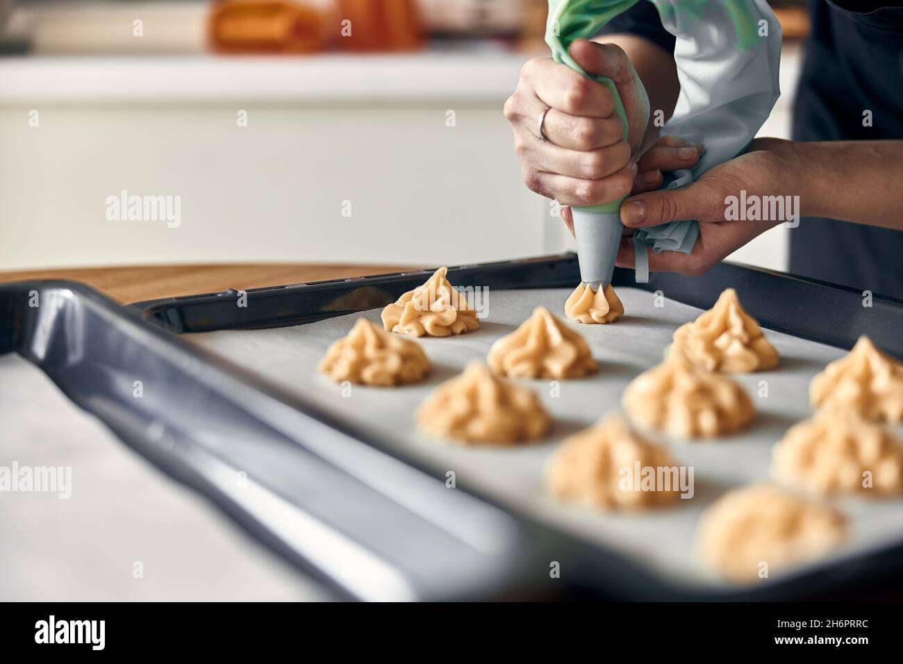 beautiful caucasian lady cook is making eclairs with help of pastry ...