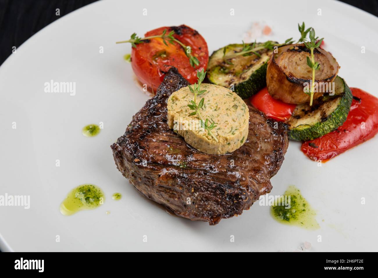 Grilled black angus strip loin steak with vegetables on white plate on ...