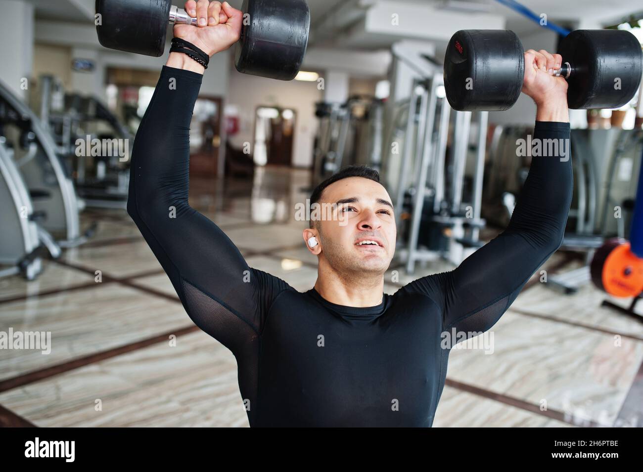 Muscular arab man training with dumbbells in modern gym Stock Photo - Alamy