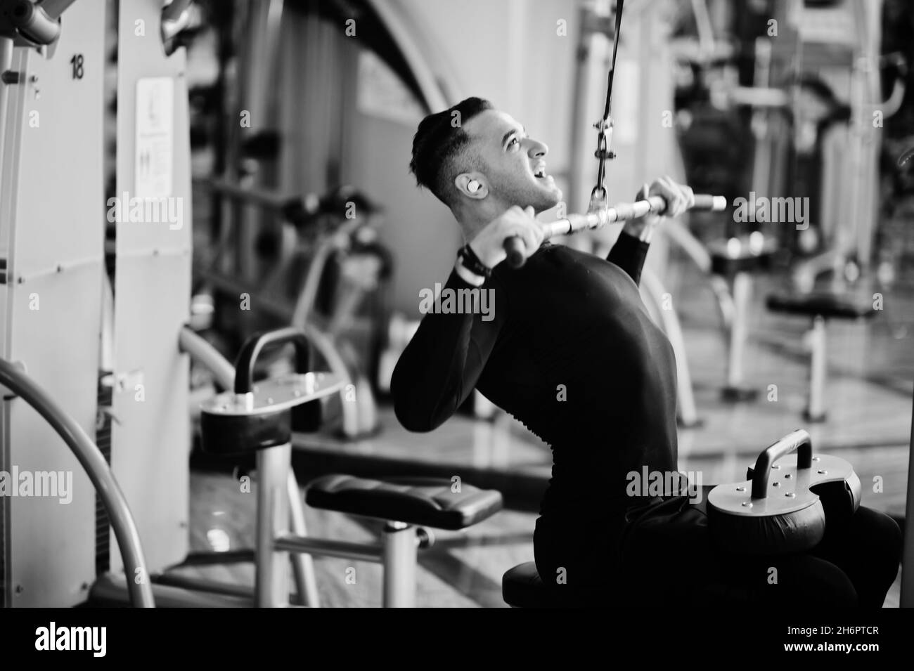 Muscular arab man training and doing workout on fitness machine in ...