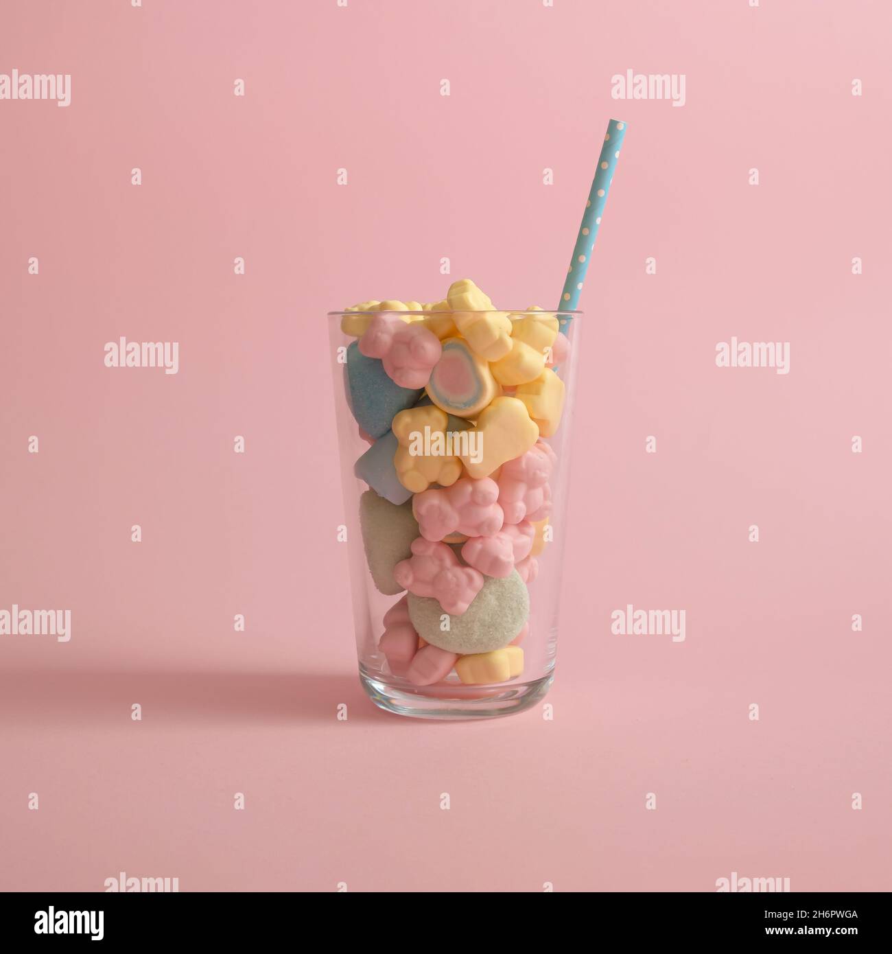 Big glass full of colorful candy with straw. Creative pastel pink ...