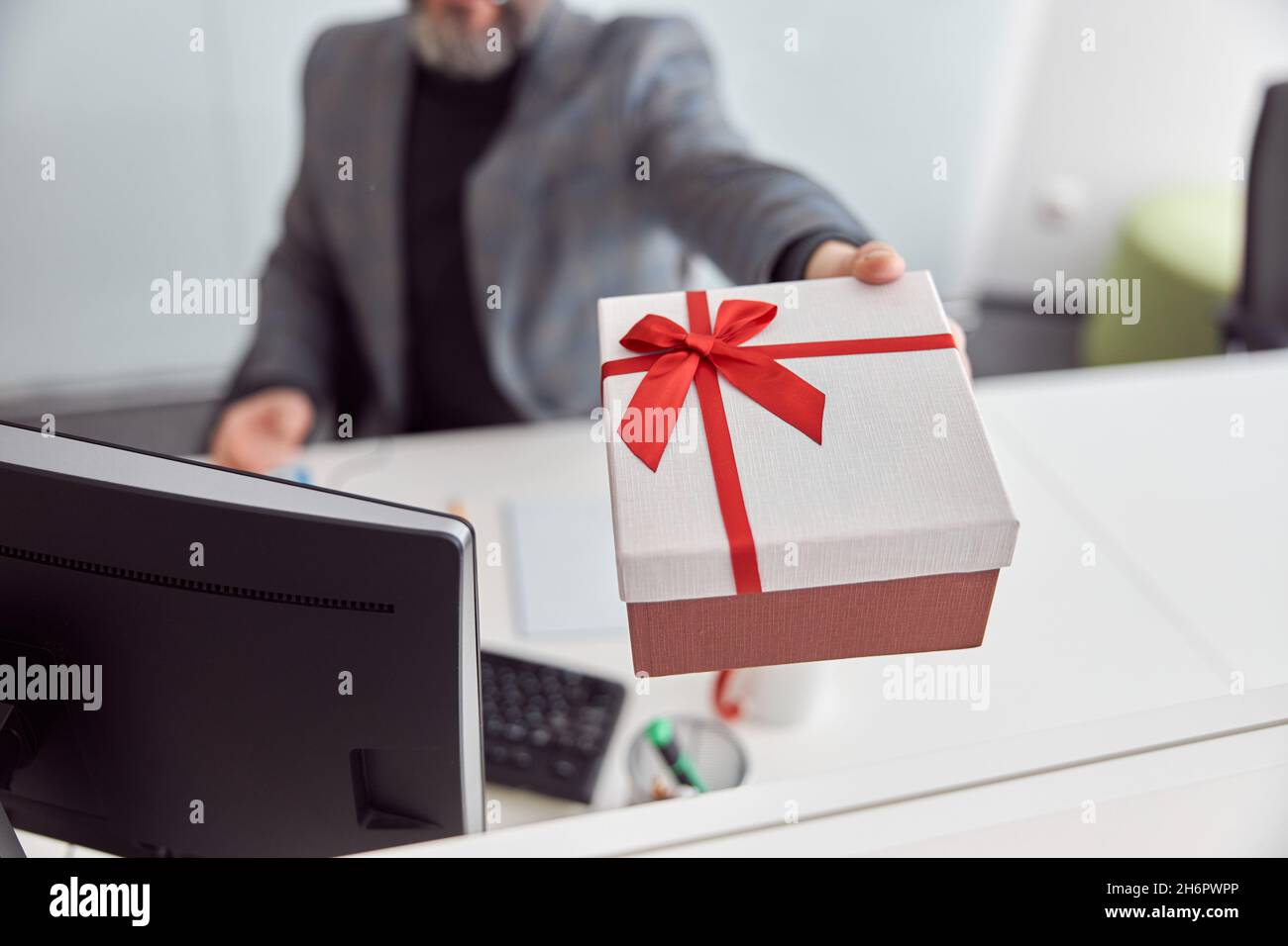 Happy office worker is holding a present and smiling Stock Photo - Alamy