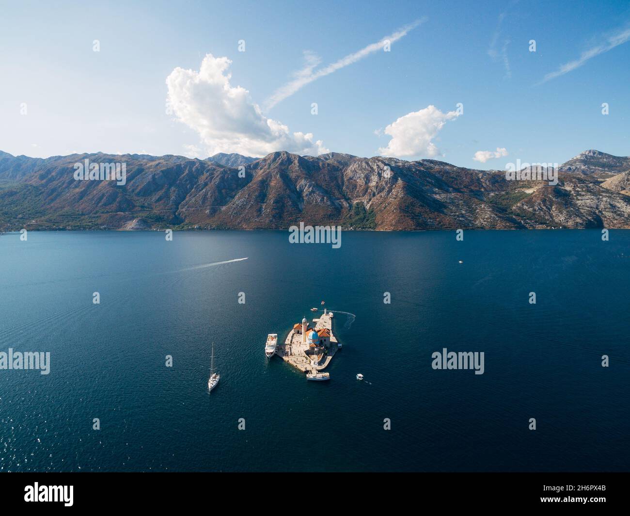 Island of Gospa od Skrpjela in the background of mountain range ...