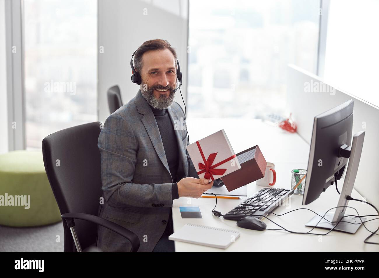 Happy office worker is holding a present and smiling Stock Photo - Alamy