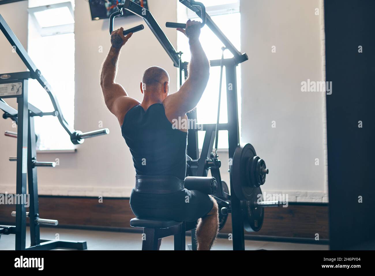 Adult bodybuilder doing heavy weight exercise for back on machine while ...