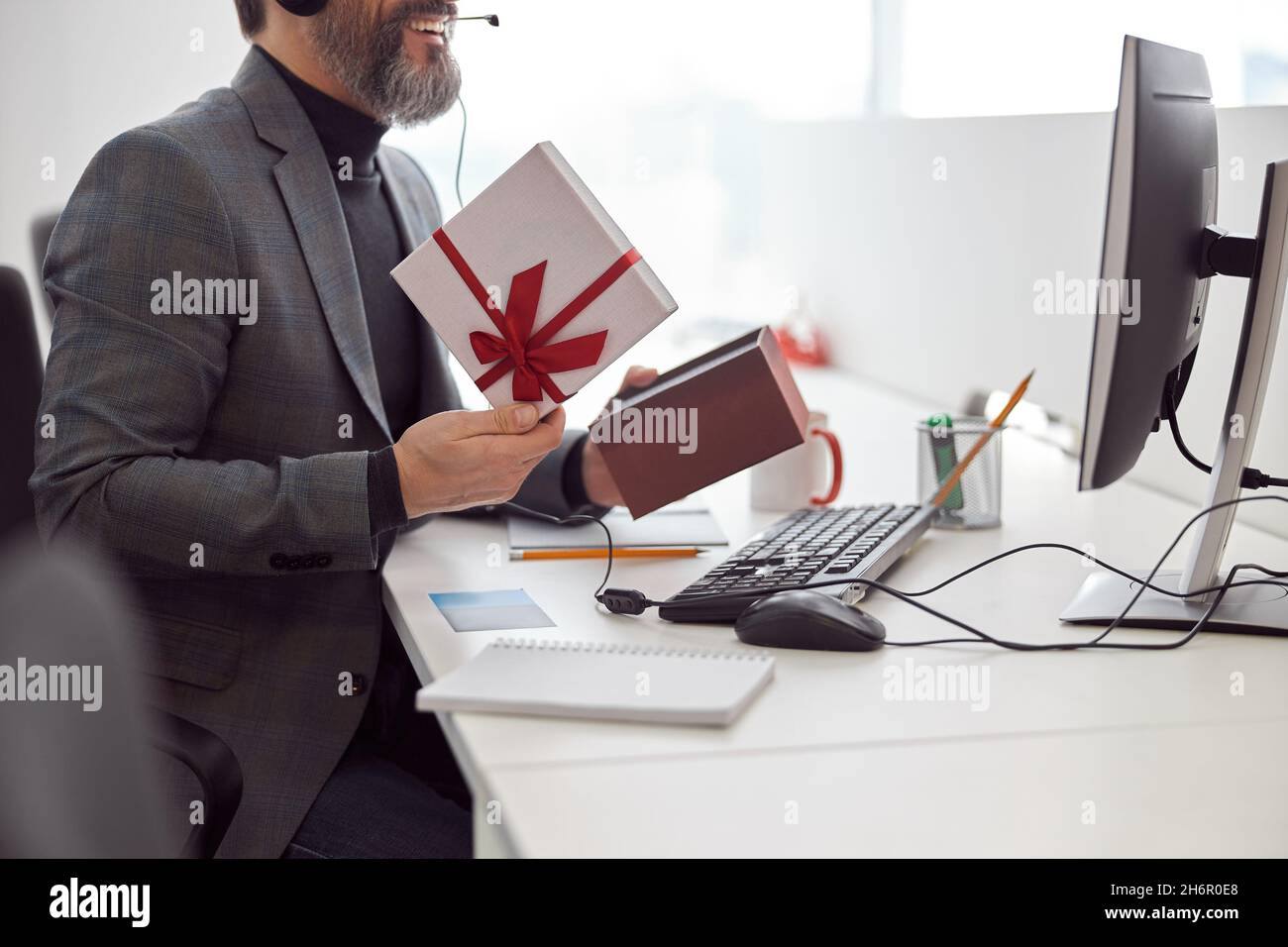 Happy office worker is holding a present and smiling Stock Photo - Alamy