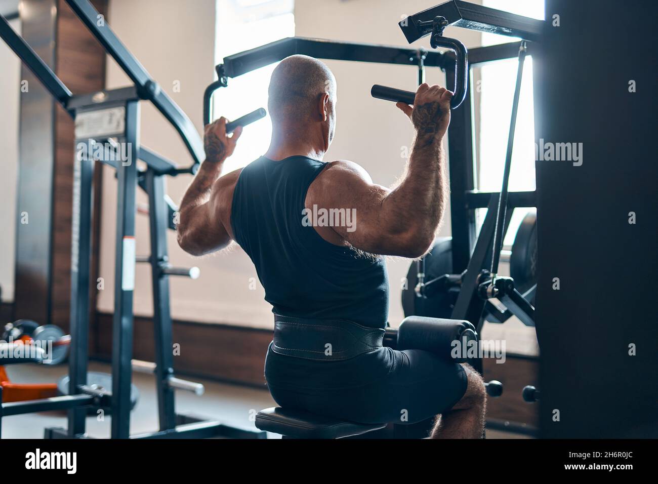 Adult bodybuilder doing heavy weight exercise for back on machine while ...