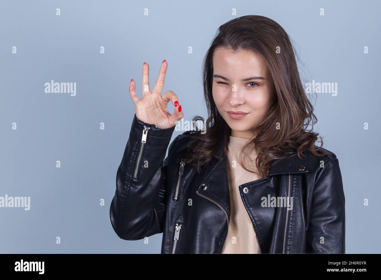 A young girl in a leather jacket makes a hand gesture ok Stock Photo ...