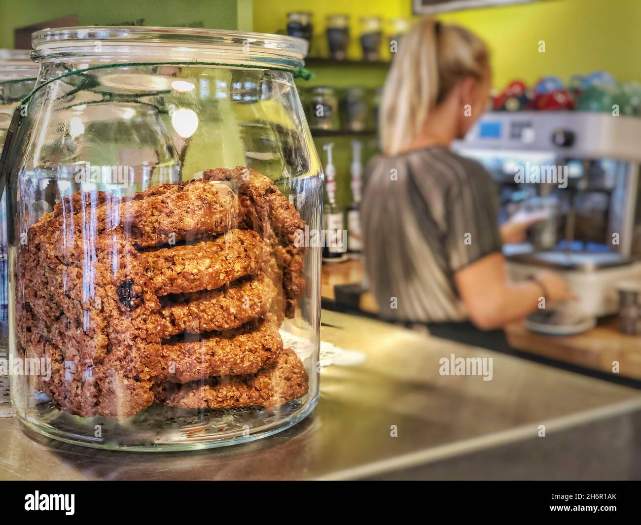 cookies in a jar on shelf in a cafe where a barista preparing coffee ...