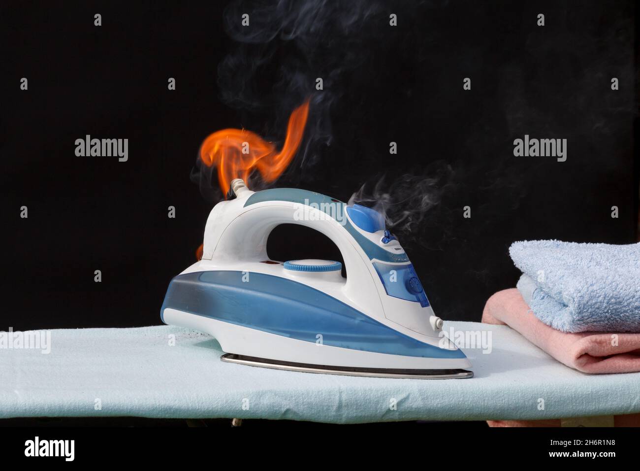 Iron on ironing board in flames fire, cause of fire Stock Photo - Alamy