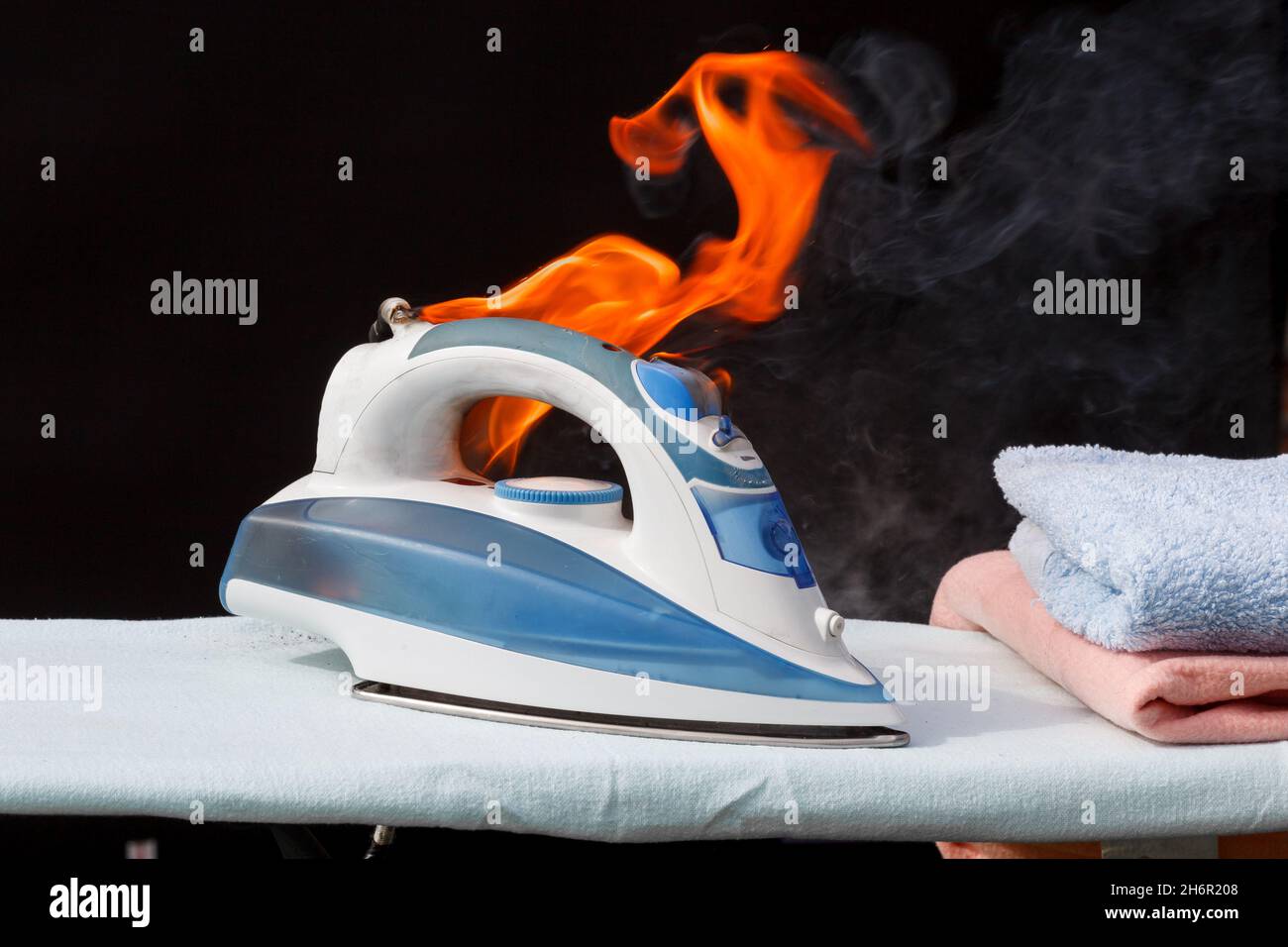 Iron on ironing board in flames fire, cause of fire Stock Photo - Alamy