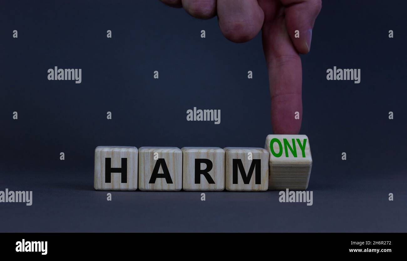 From harm to harmony. Businessman turns the wooden cube and changes ...