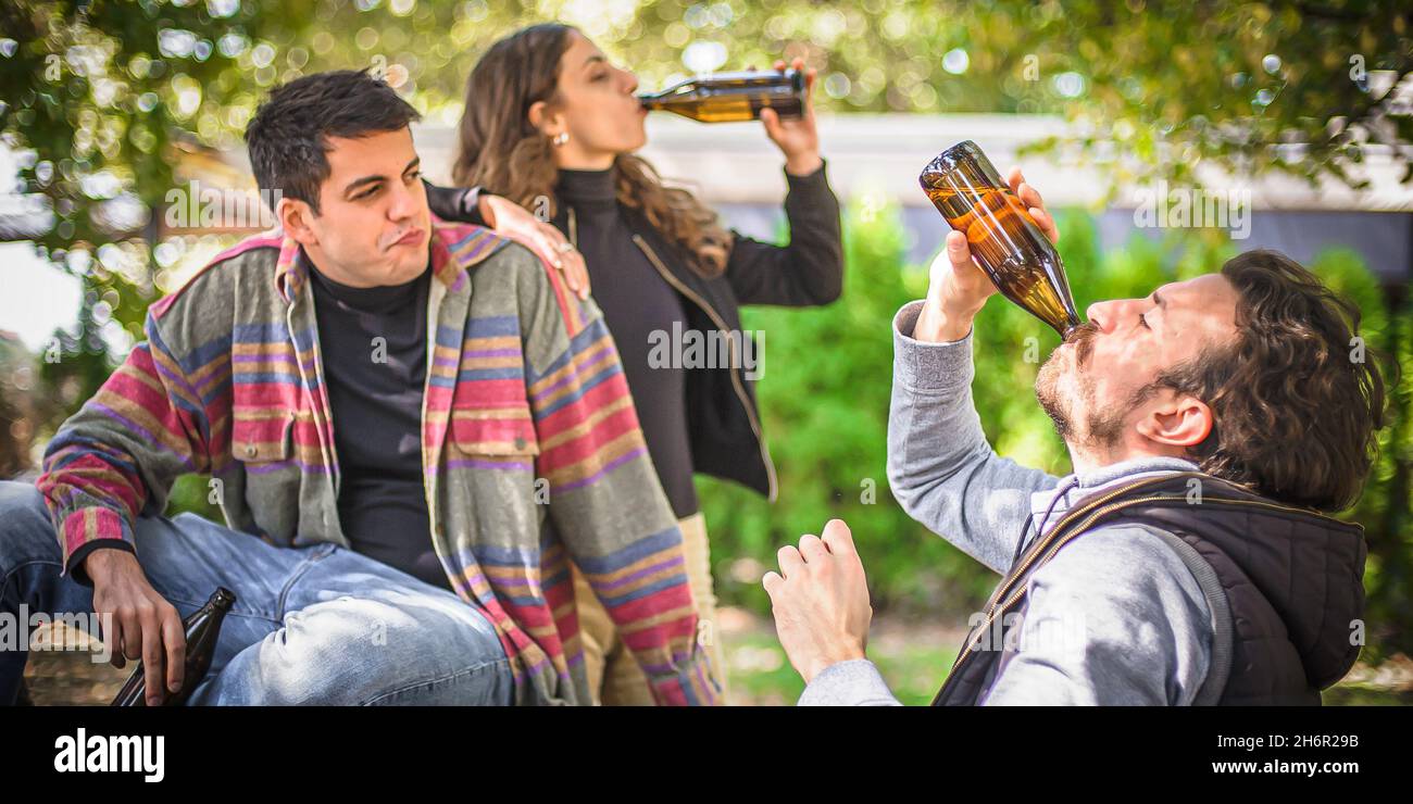 Young group of friends, female and male, chugging beer from bottle on ...