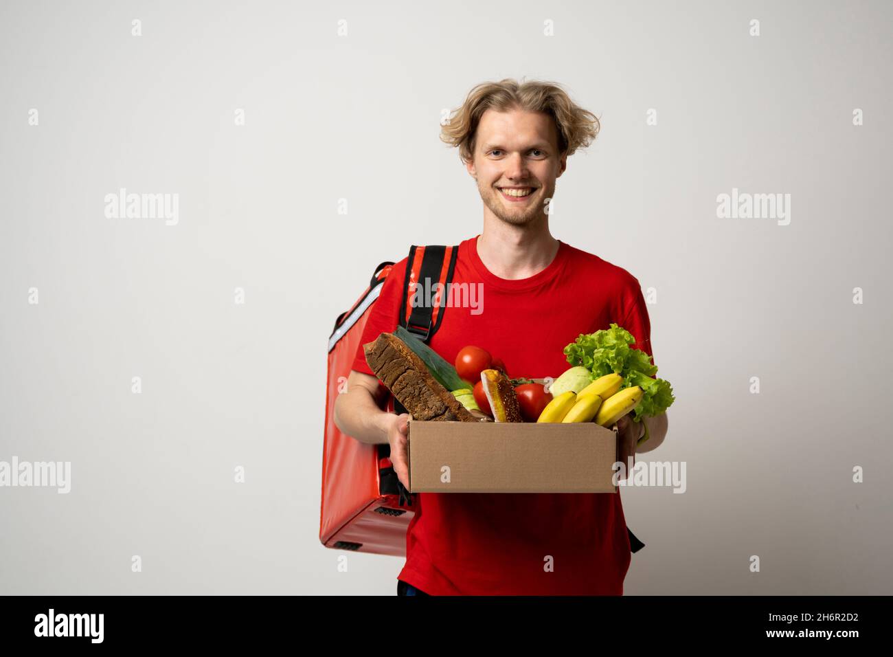 Handsome delivery man carrying package box of grocery food and drink ...