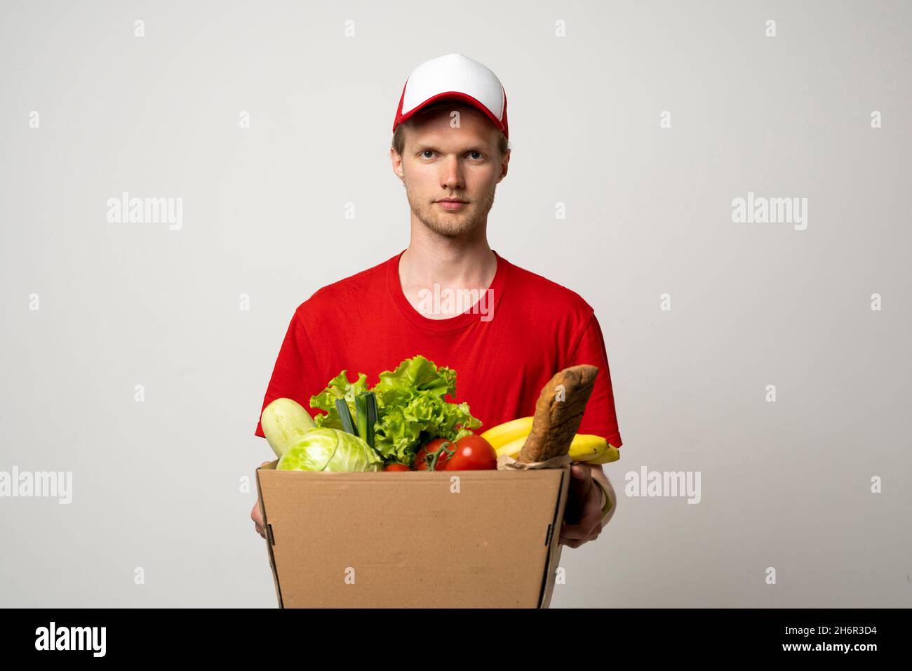 Delivery man in red uniform holds craft paper packet with food isolated ...