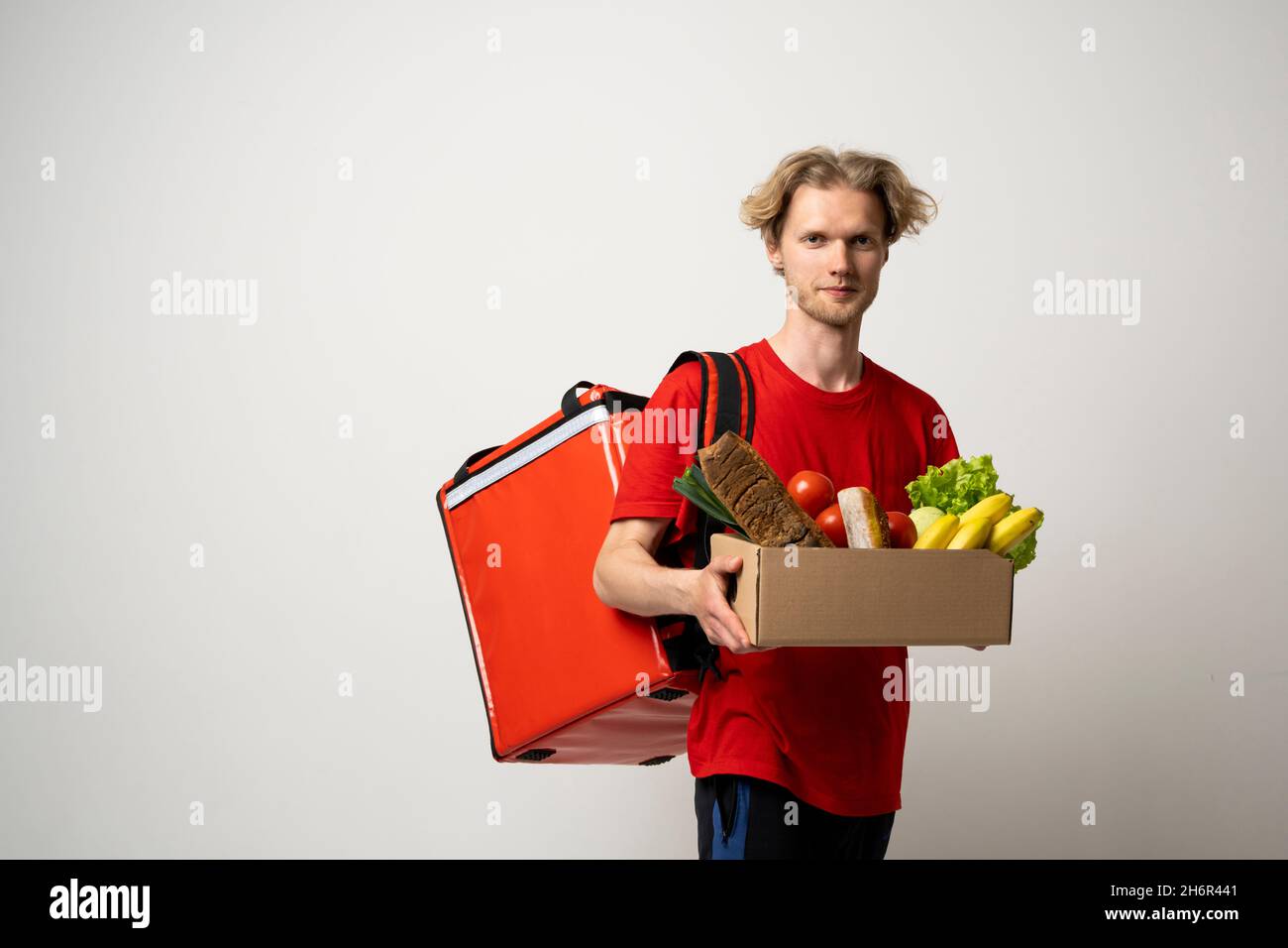 Food delivery service. Portrait of pleased delivery man in red uniform ...